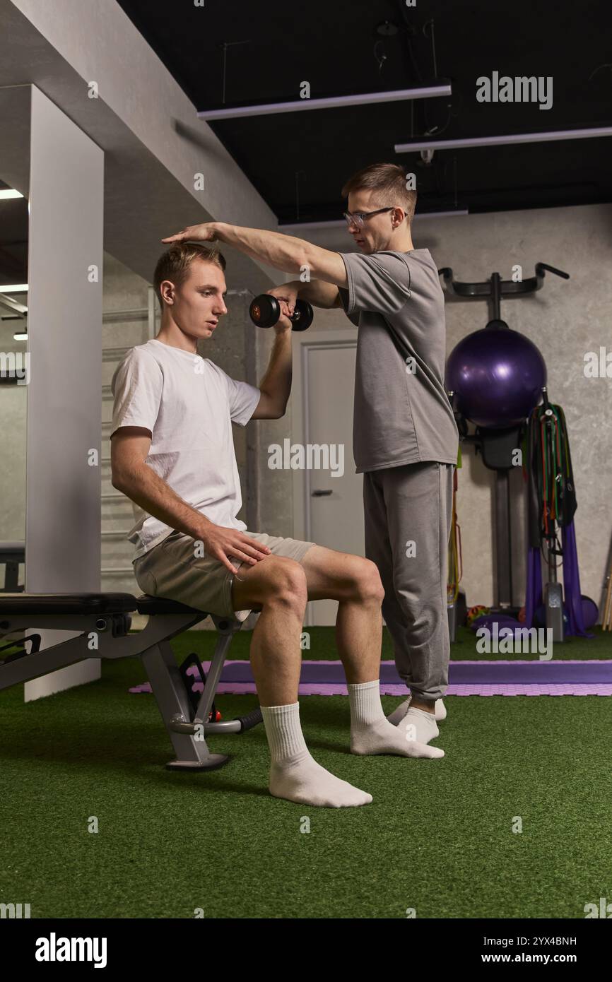 Man seated on fitness bench performing shoulder rehabilitation ...