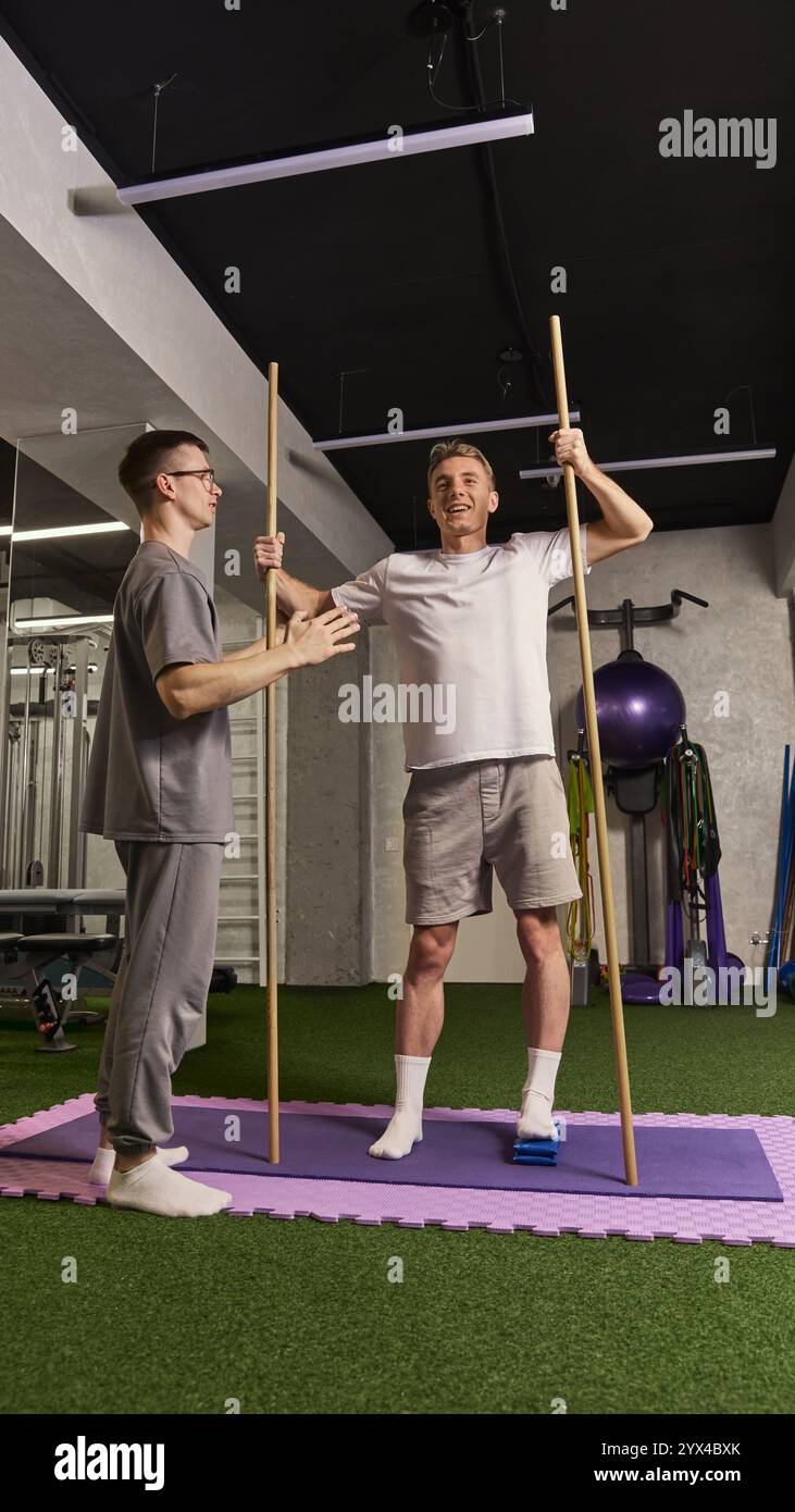 Man standing on foam pad, holding two sticks for support while ...