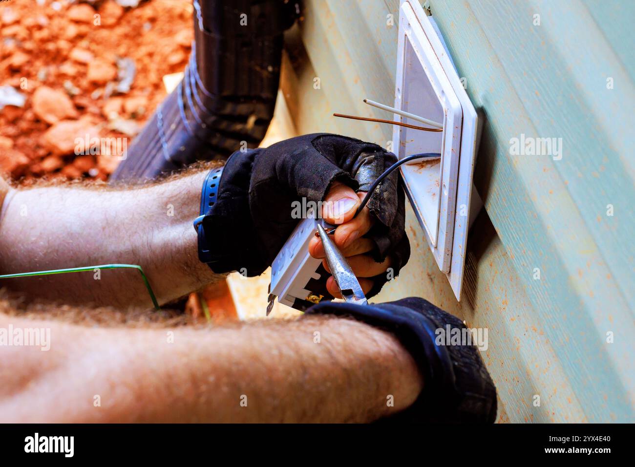 An electrician hand is holding an outlet plug that is affixed to ...