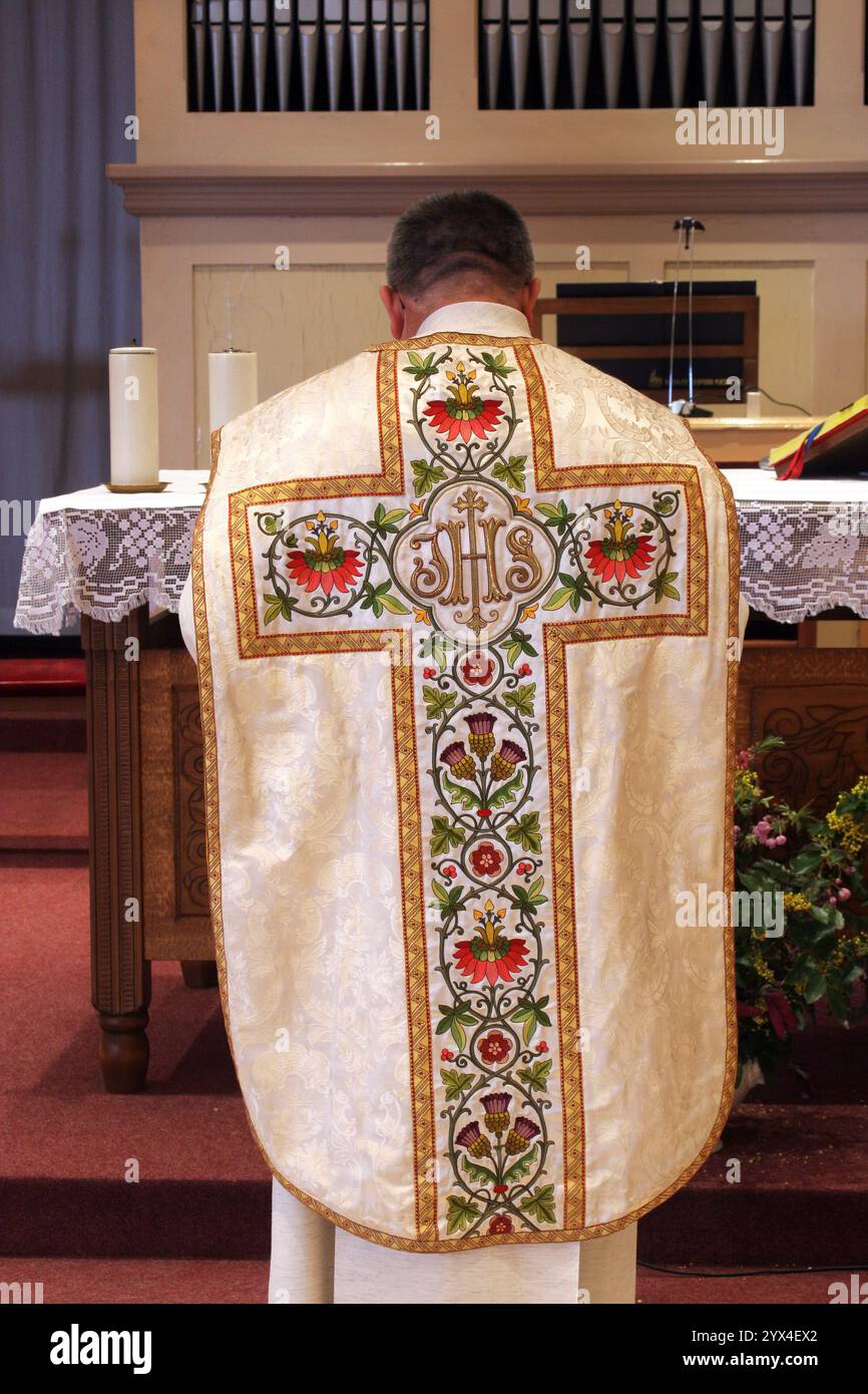 A priest in a white chasuble celebrates mass in the church of ...