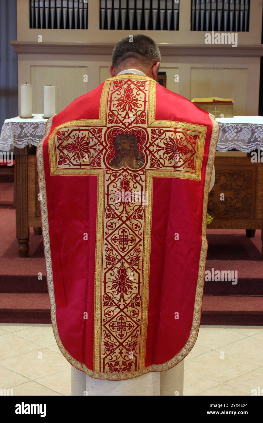 A priest in a red chasuble celebrates mass in the church of Assumption ...