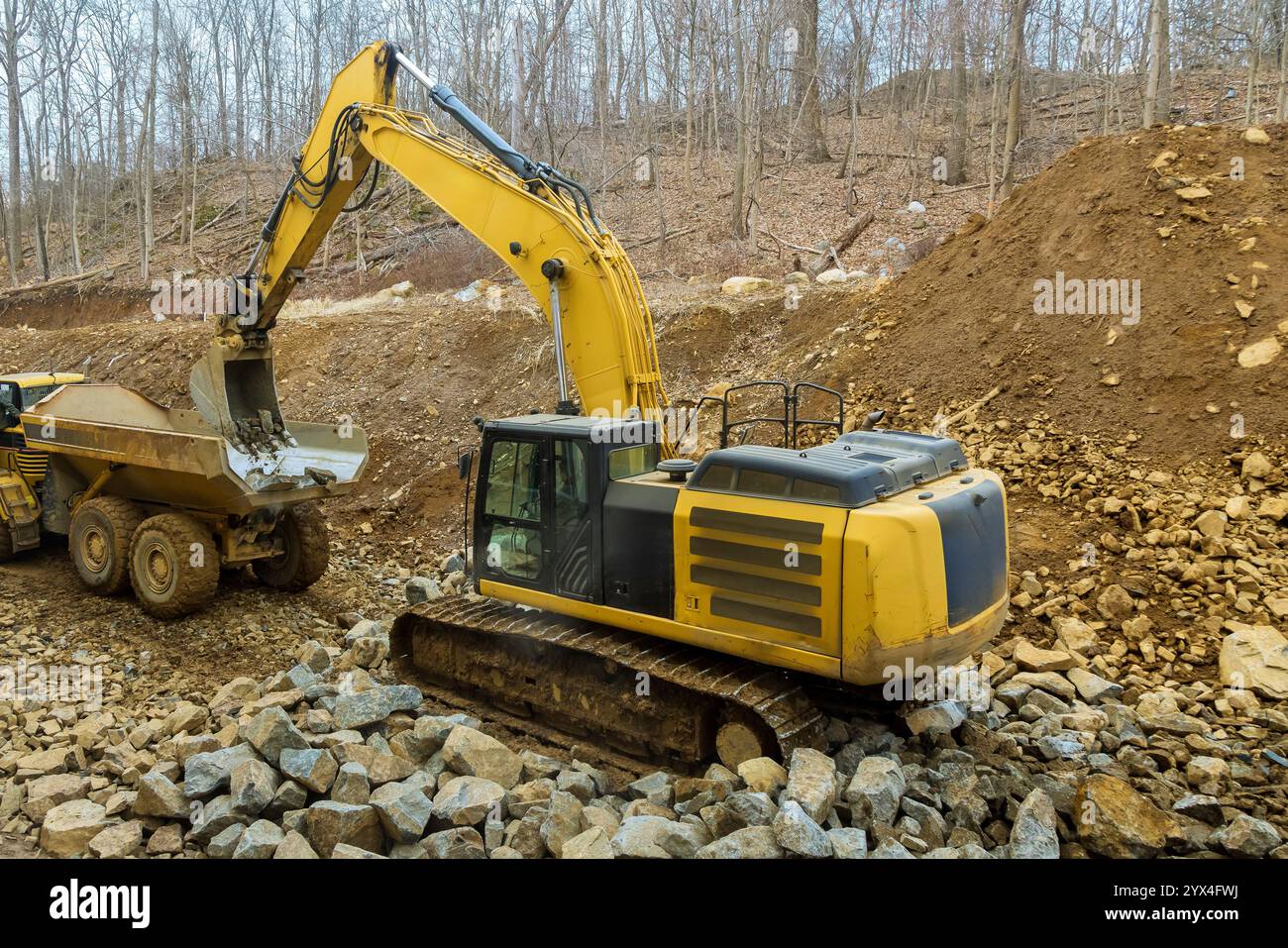 An excavator is loading gravel into truck while working on construction ...