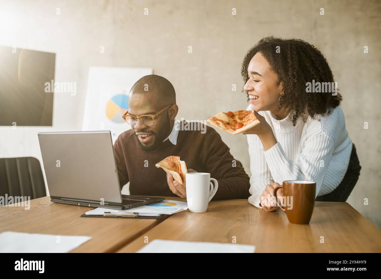 Two colleagues having pizza during office meeting break Stock Photo - Alamy