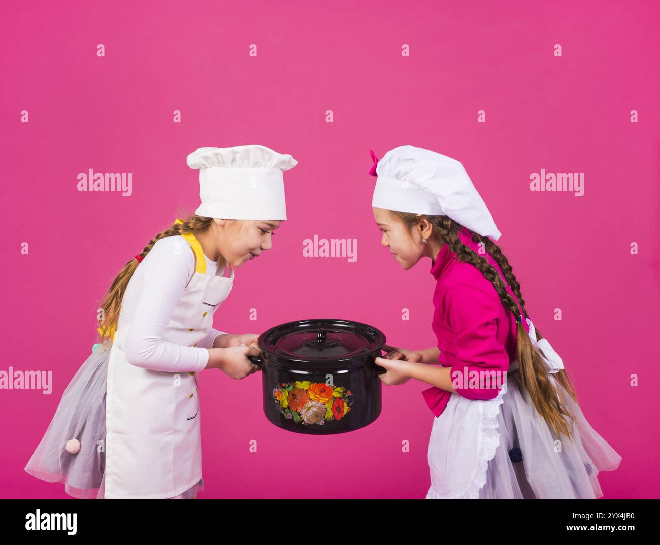 Two girls cooks carrying heavy pot Stock Photo - Alamy