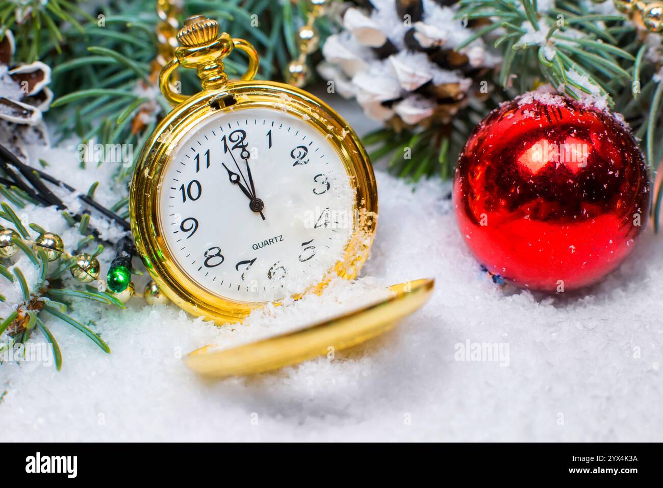 A vintage clock in the snow against the background of a Christmas tree ...