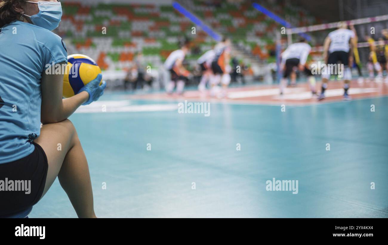 Girl with face mask and voleyball ball in the hands in the background ...