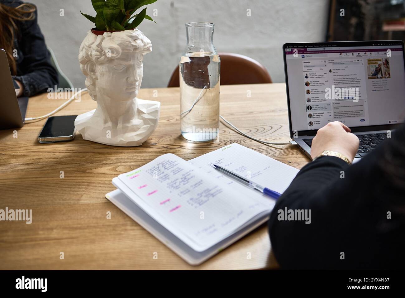 Creative office setting with decorative bust planter, open notebook ...