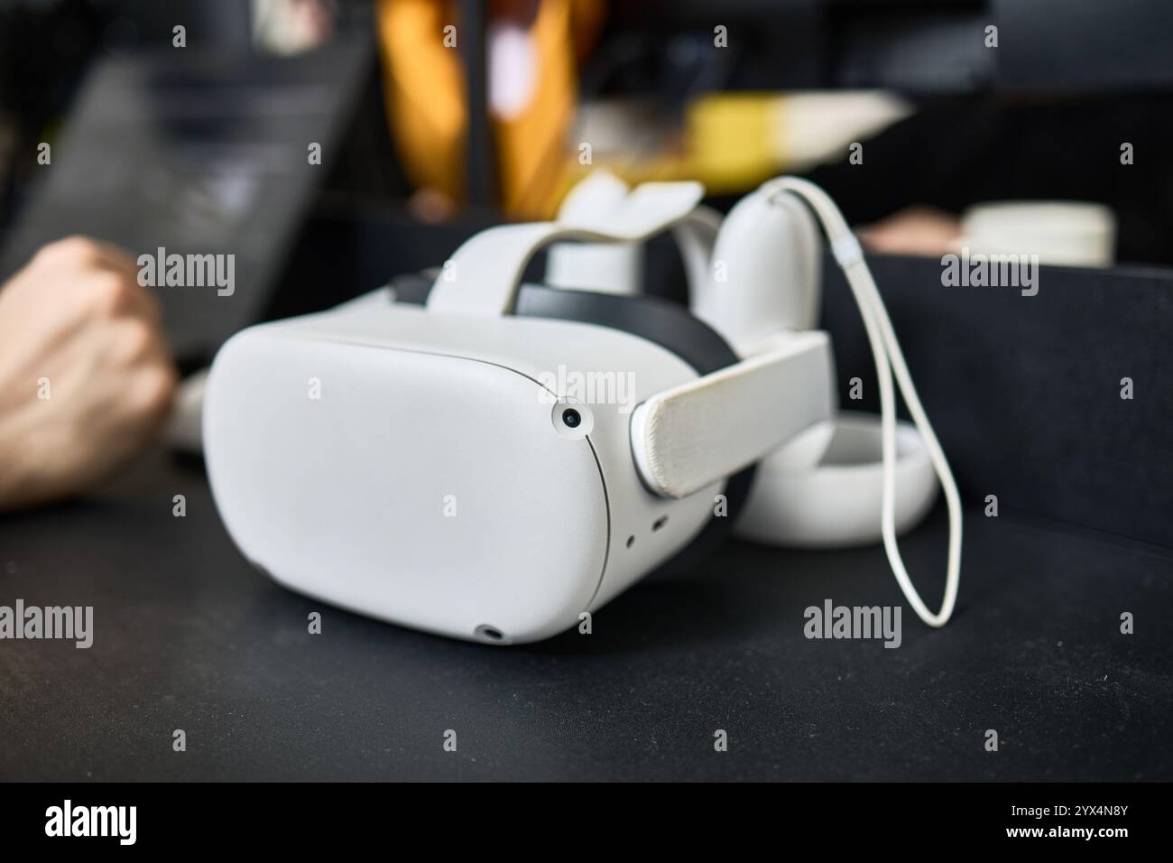 VR goggles placed on a desk with an out-of-focus individual in a ...