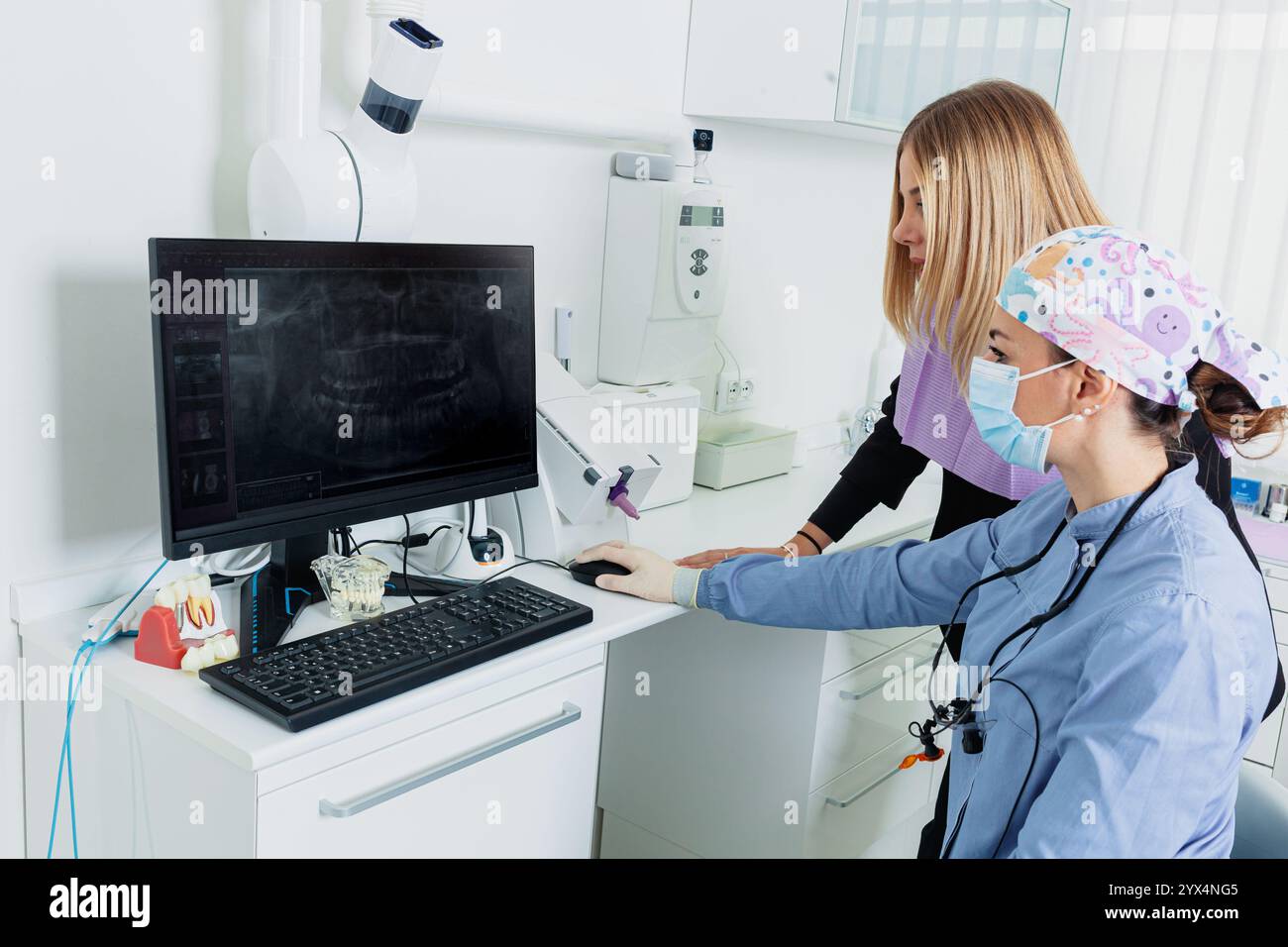 Dentist showing a dental x ray to her patient on a computer screen in a ...