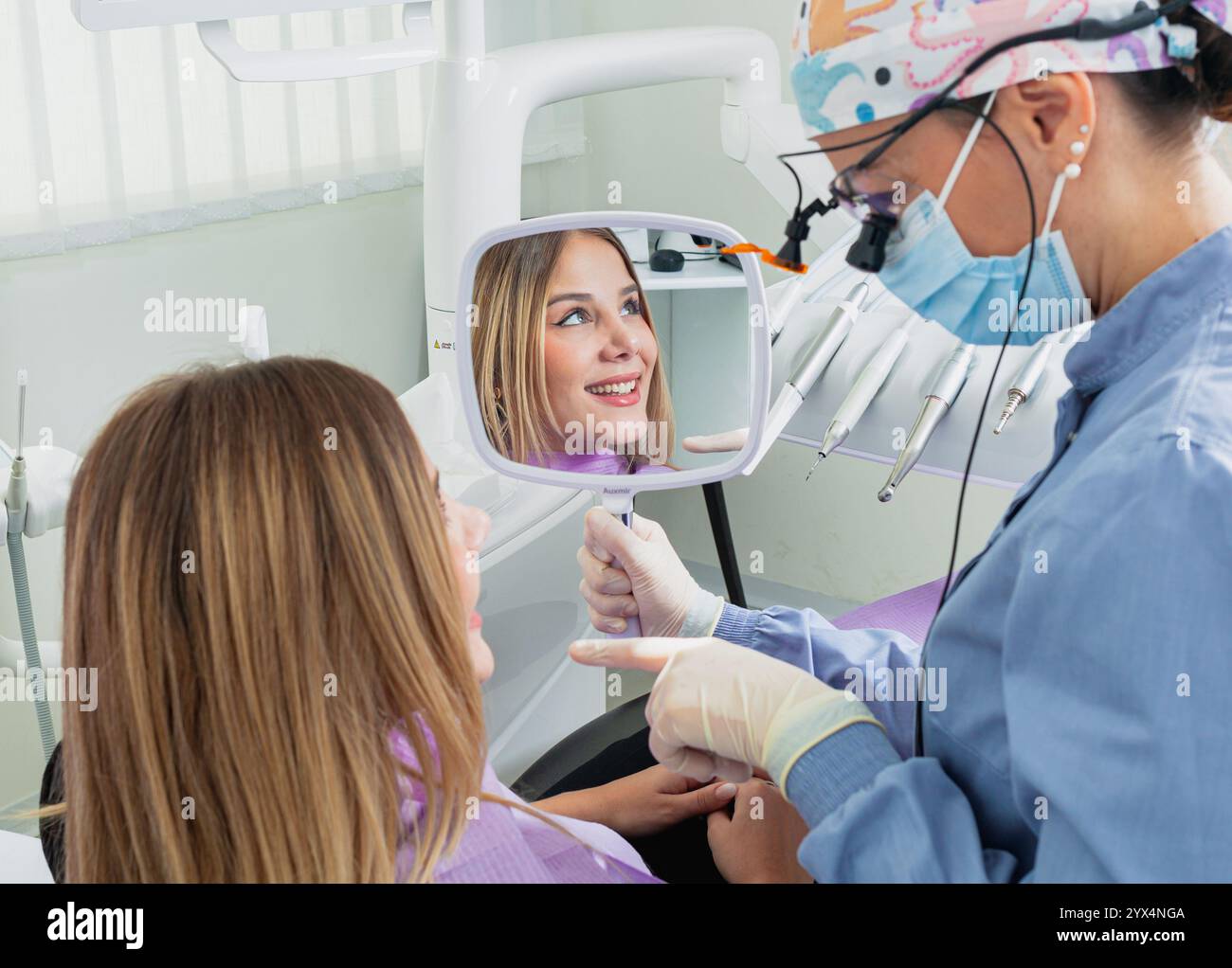Female dentist demonstrating treatment results with a mirror to a ...