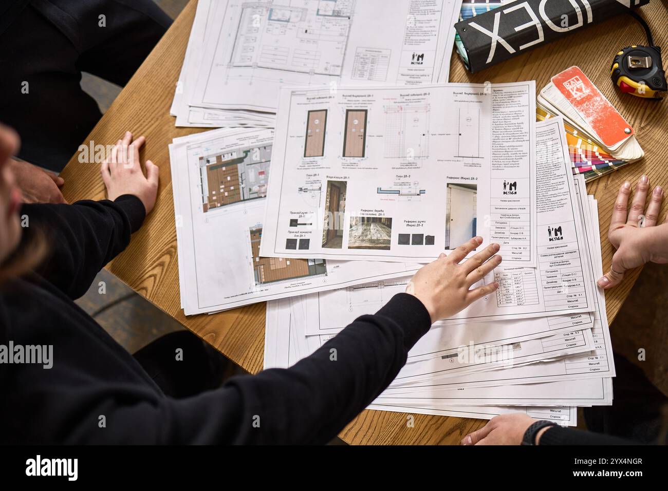 Architectural plans discussed by designers on wooden table with visible ...