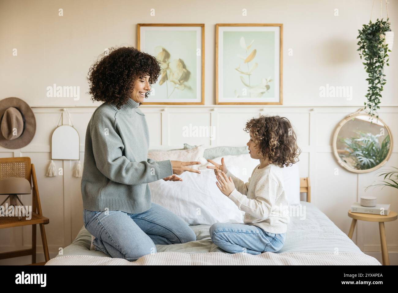 A cheerful mother and her child playing a game of rock-paper-scissors ...