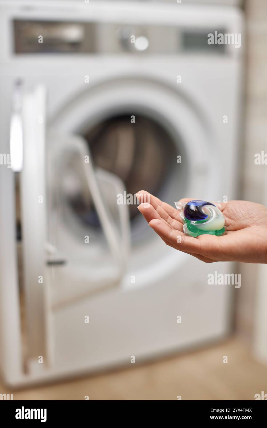 female hand putting capsule pod detergent for washing clothes into ...
