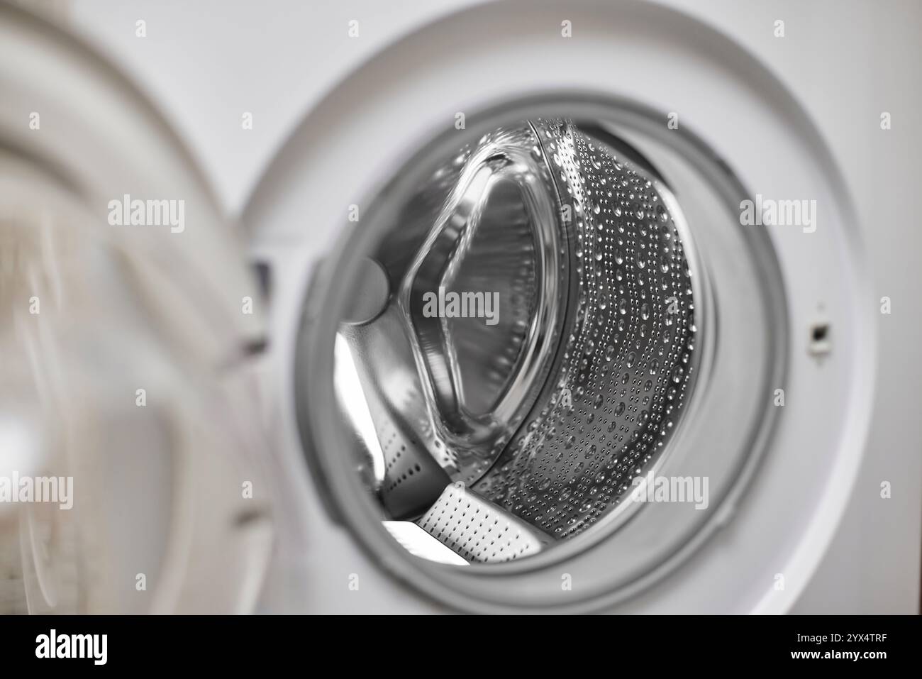 Open door of empty washing machine with metal drum in laundry room ...