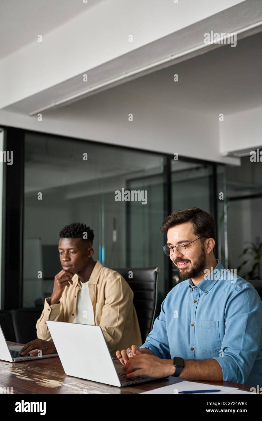 Two busy diverse businessmen employees using laptops working in office ...
