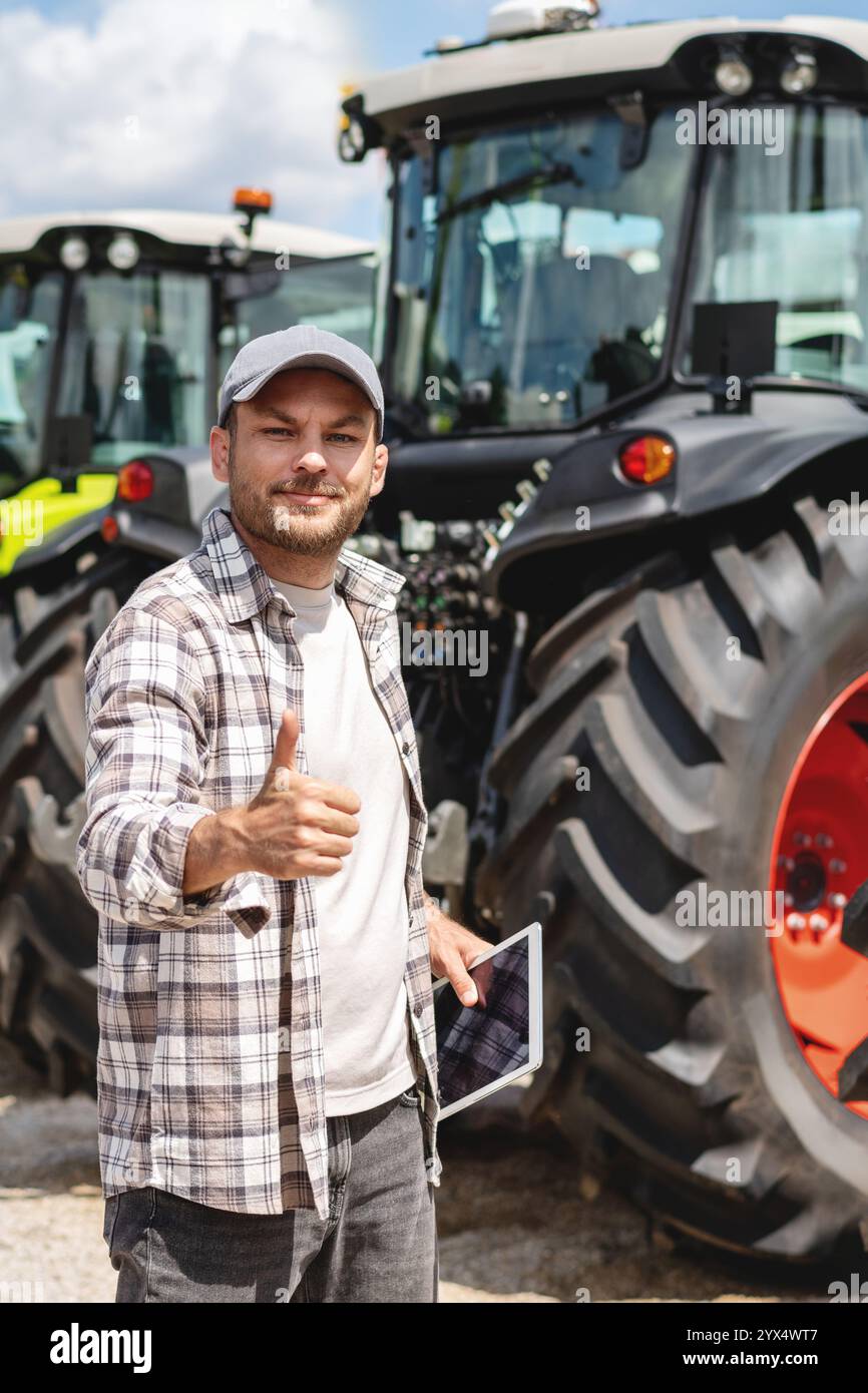 Vertical portrait male farmer stands next farm tractors and gestures ...