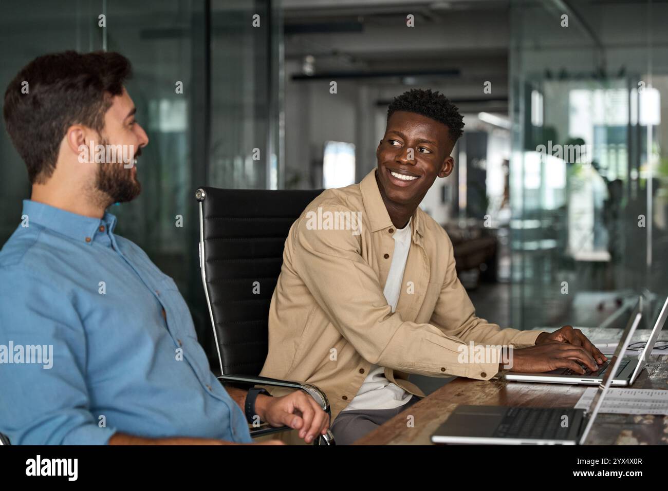 Happy diverse workers team talking at work using computer sharing ideas ...