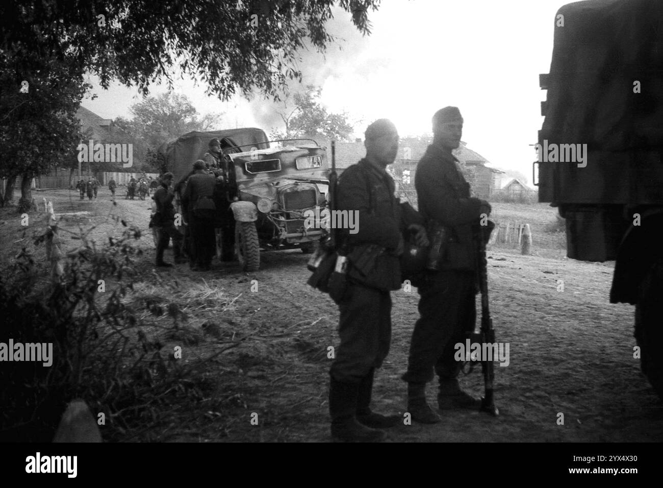 Russia 1943: German soldiers on a vehicle, behind them burning village ...