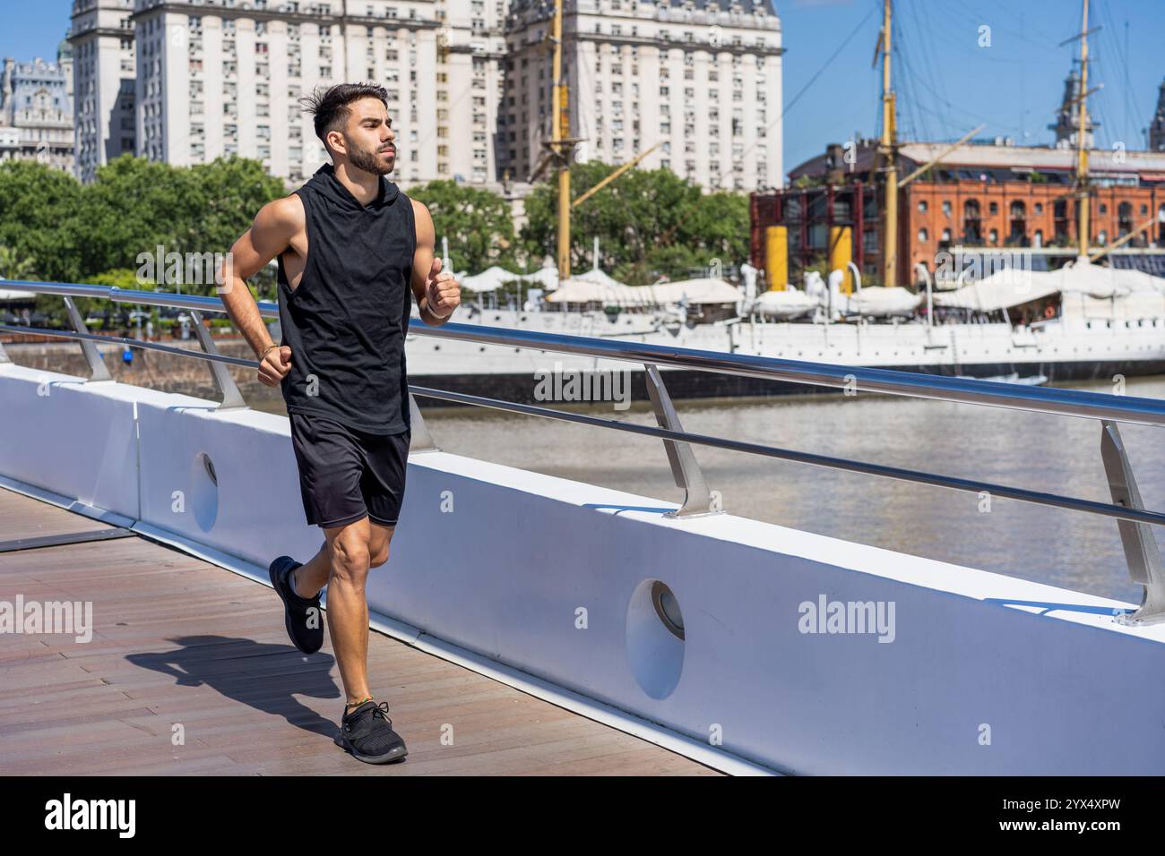 Dynamic male jogger enjoying a sunny day on a city bridge Stock Photo ...