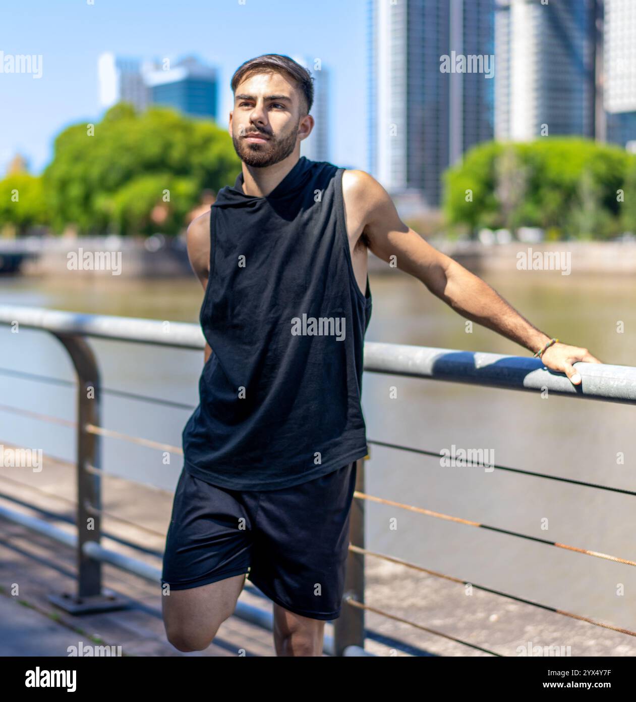 Athletic male warming up with stretches by the urban waterfront Stock ...