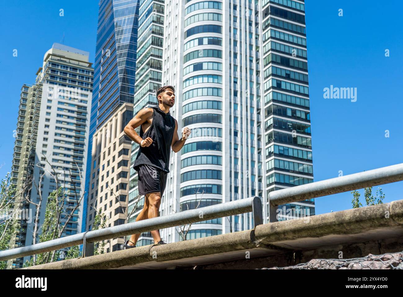 Athletic male jogging through an urban landscape with modern buildings ...