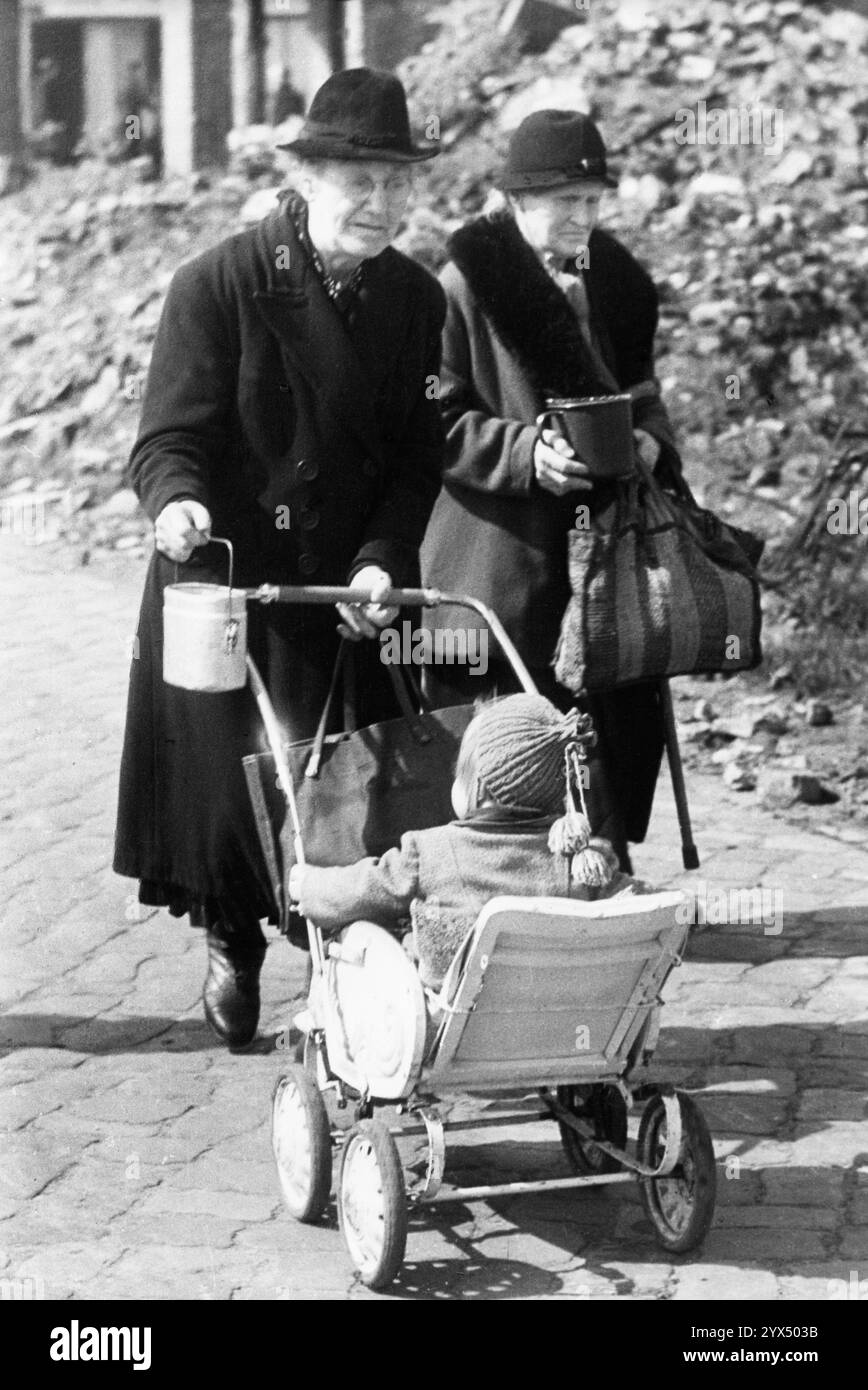 Old lady pushing a child in a child's cart, holding a cooking utensil ...