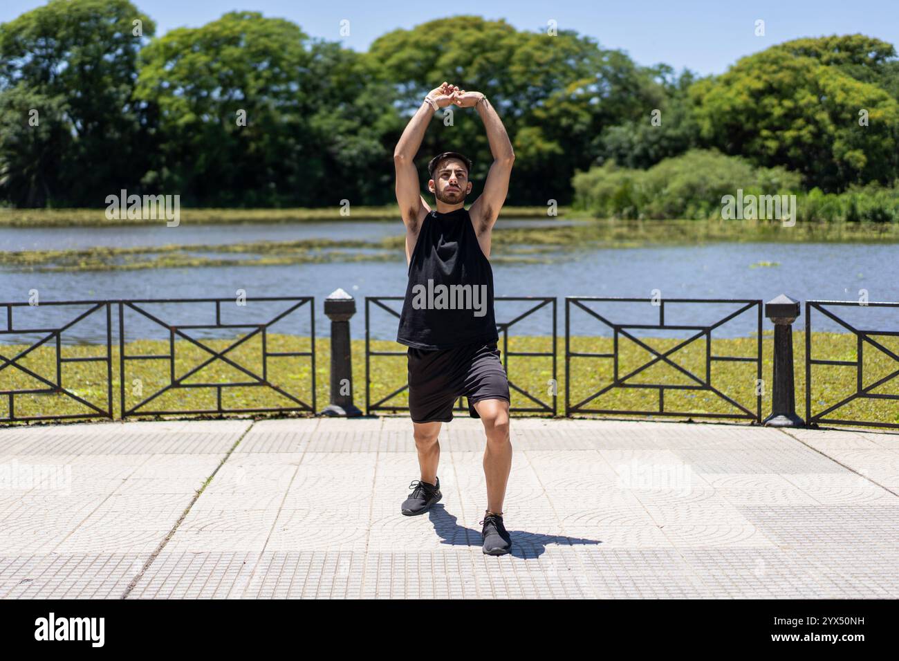 Energized young man stretches by the water after an intense workout in ...