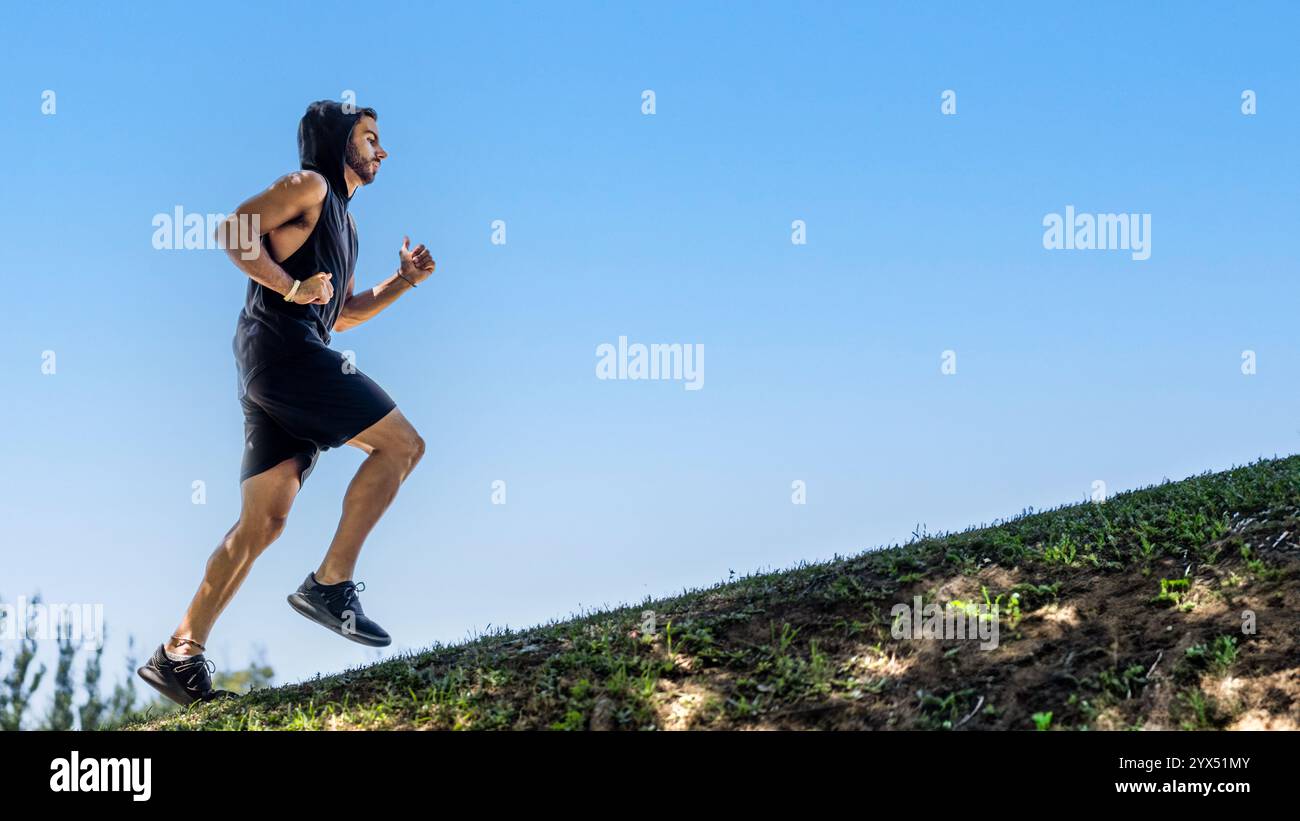Athletic young man enjoying a challenging run on rolling terrain in a ...