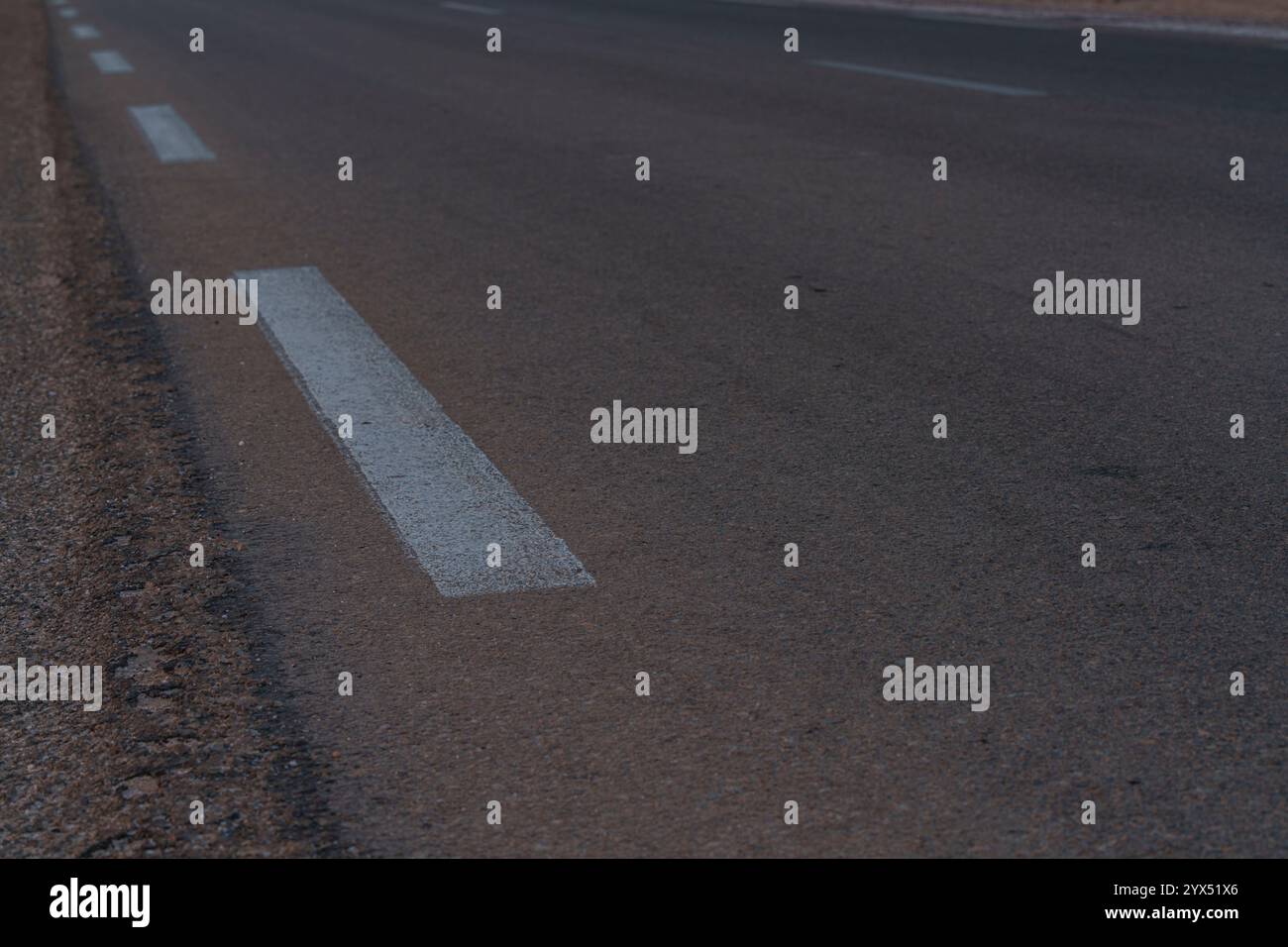 an asphalt road leading through a flat section of desert to the horizon ...