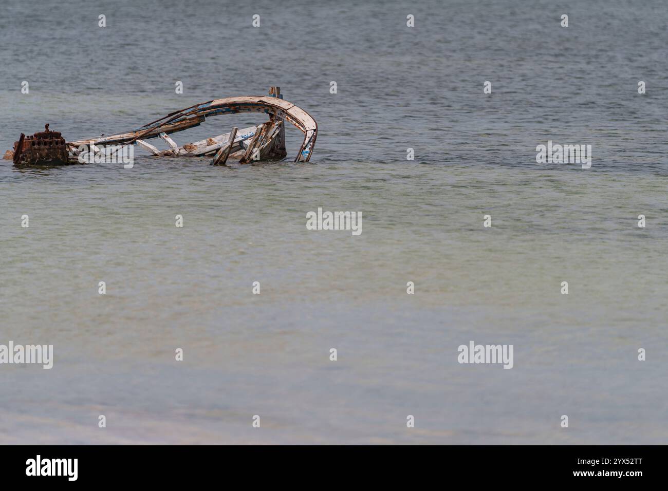 A partially submerged and dismantled boat in the shallow part of the ...