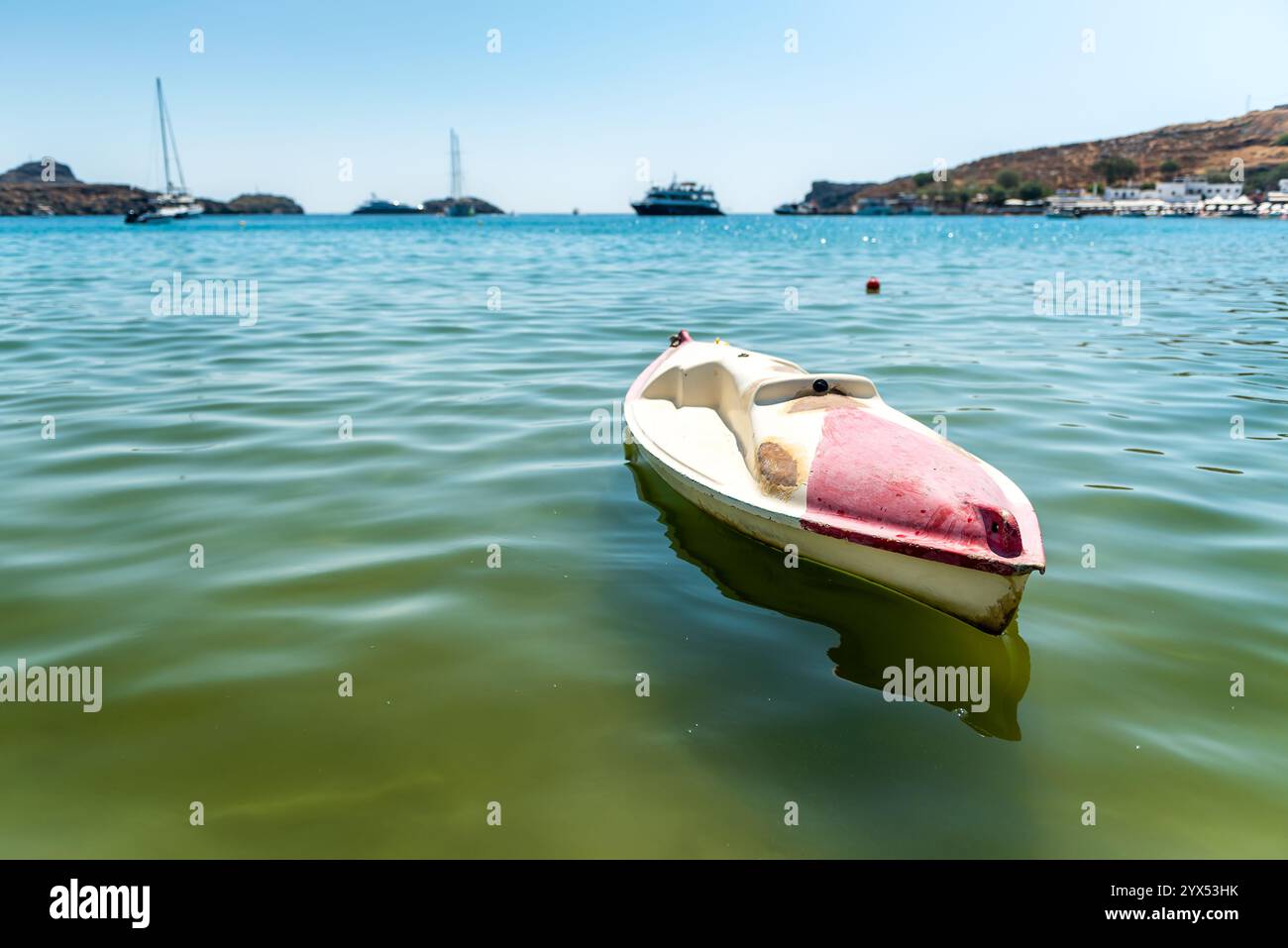 Old kayak boat in shallows of sandy beach in Bay of Lindos, with Lindos ...