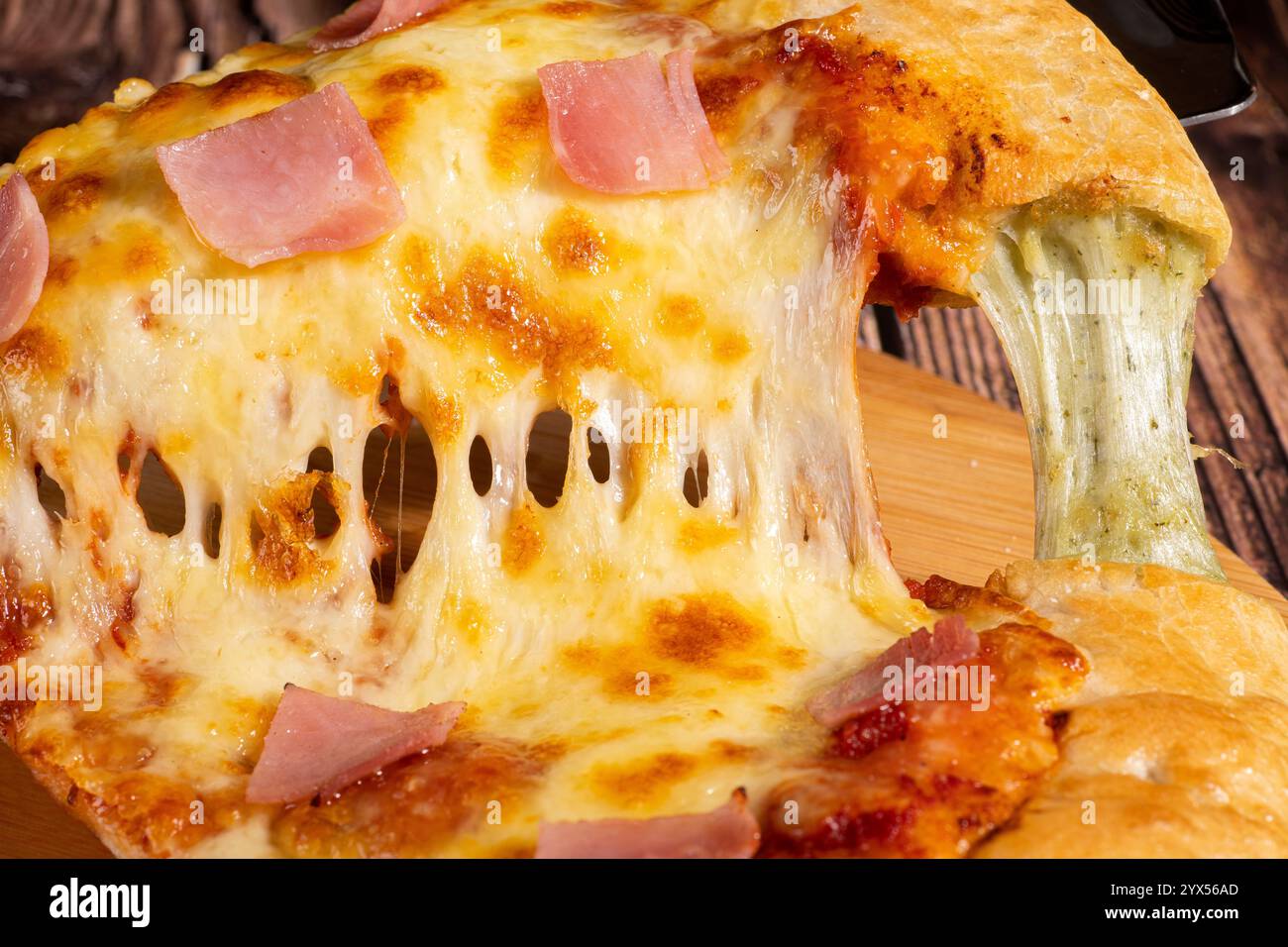 Delicious pizza slice with melted cheese and ham lifting up Stock Photo - Alamy