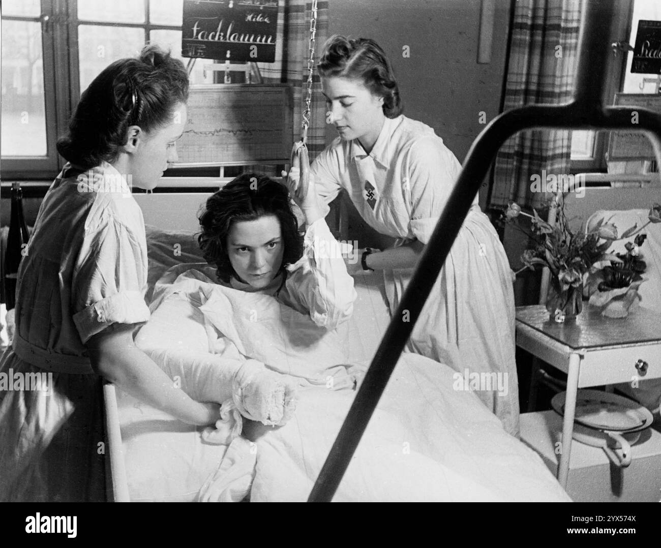 Two nurses are caring for a patient. The nurse on the right has a ...