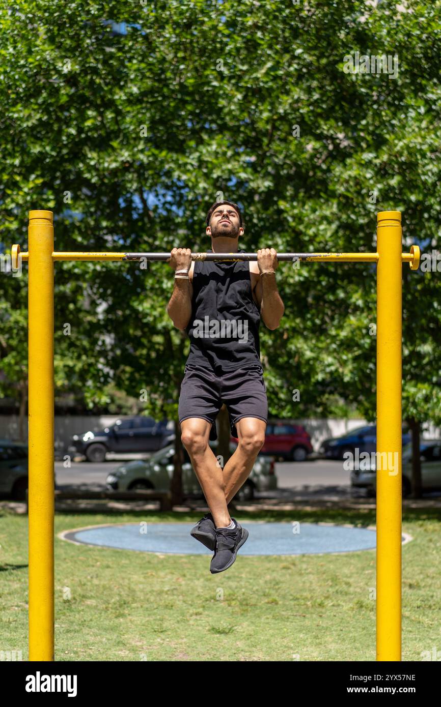 Fit young man executing pull-ups in a park setting Stock Photo - Alamy
