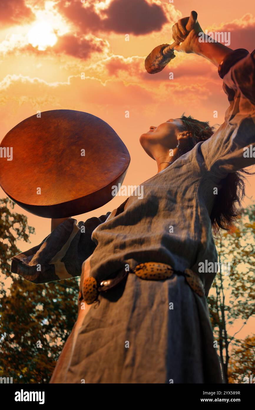 Shaman woman performs a ritual with a tambourine at sunset in the ...