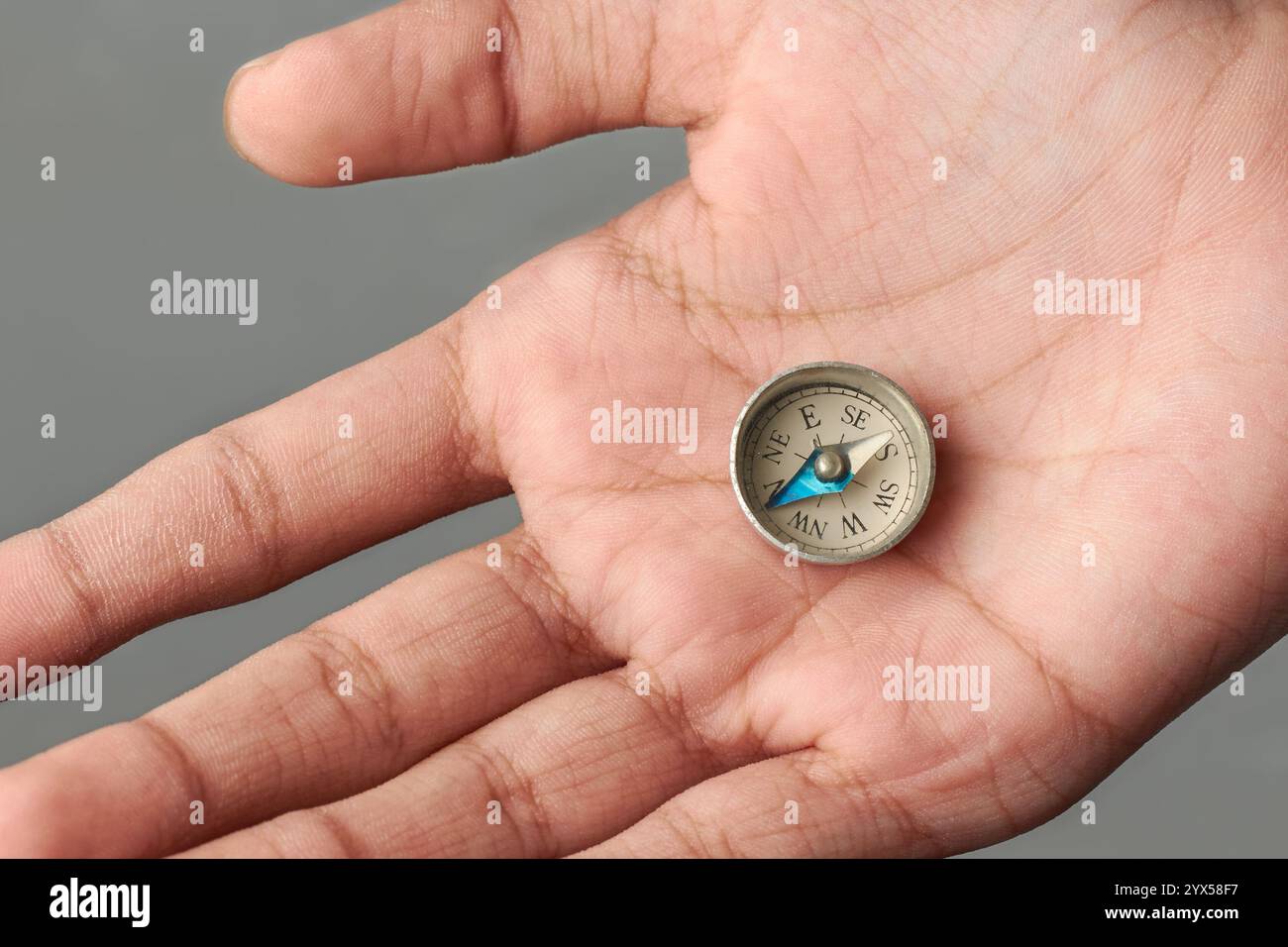 Close Up Of Hand Holding Small Round Vintage Pocket Compass Isolated Gray Background White Dial