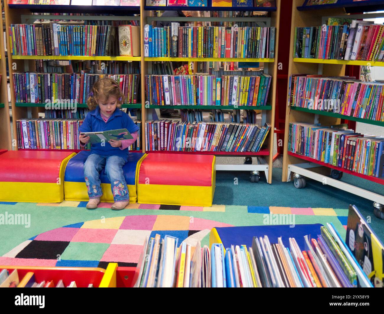 Young girl preschool child in children's section of a public library ...