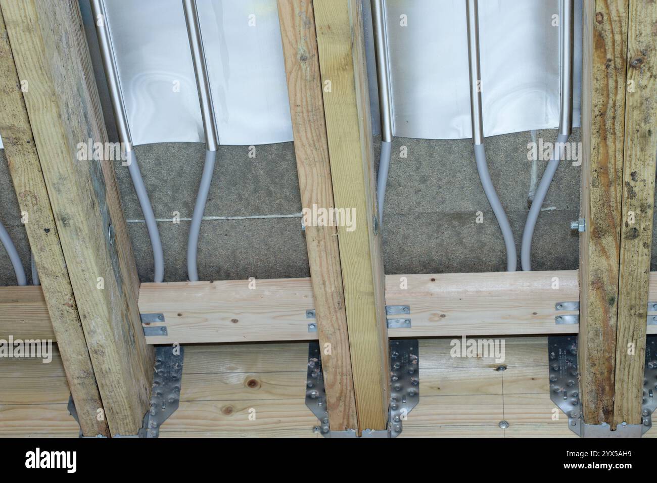 Timber joists of a timber framed building. Underfloor heating pipes ...