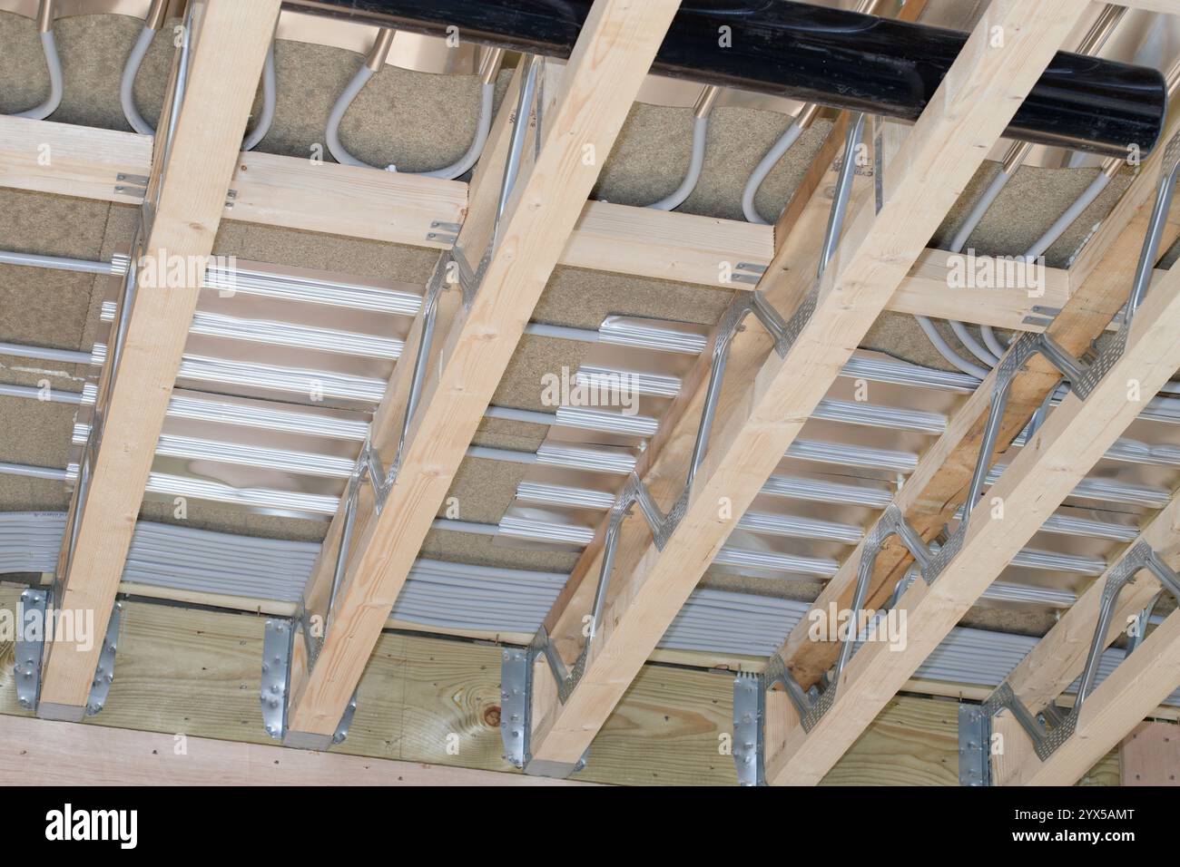 Timber joists of a timber framed building. Underfloor heating pipes ...