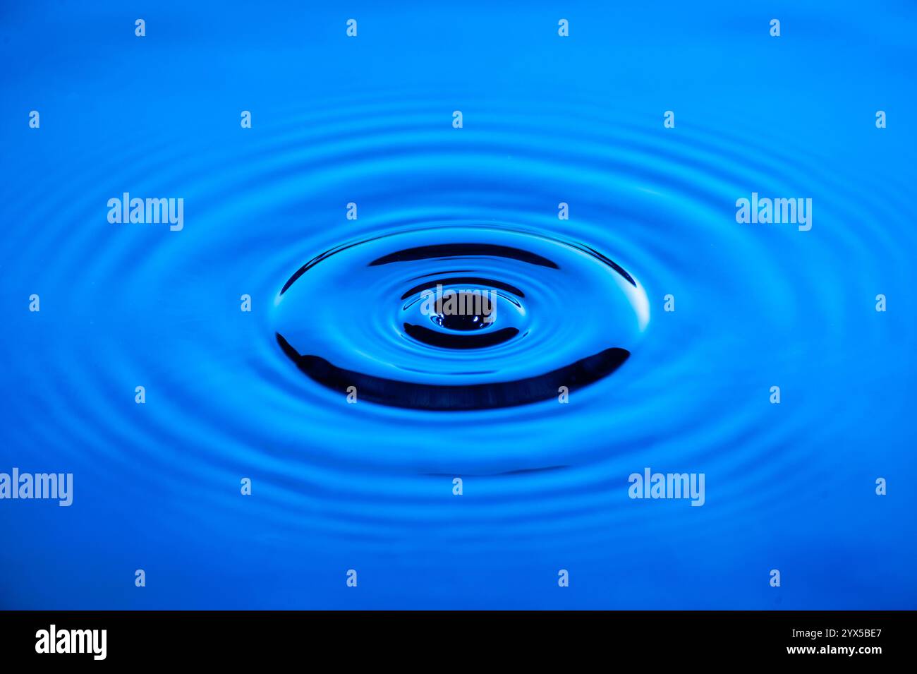 Waves of water caused by the falling droplets with blue lighting Stock ...
