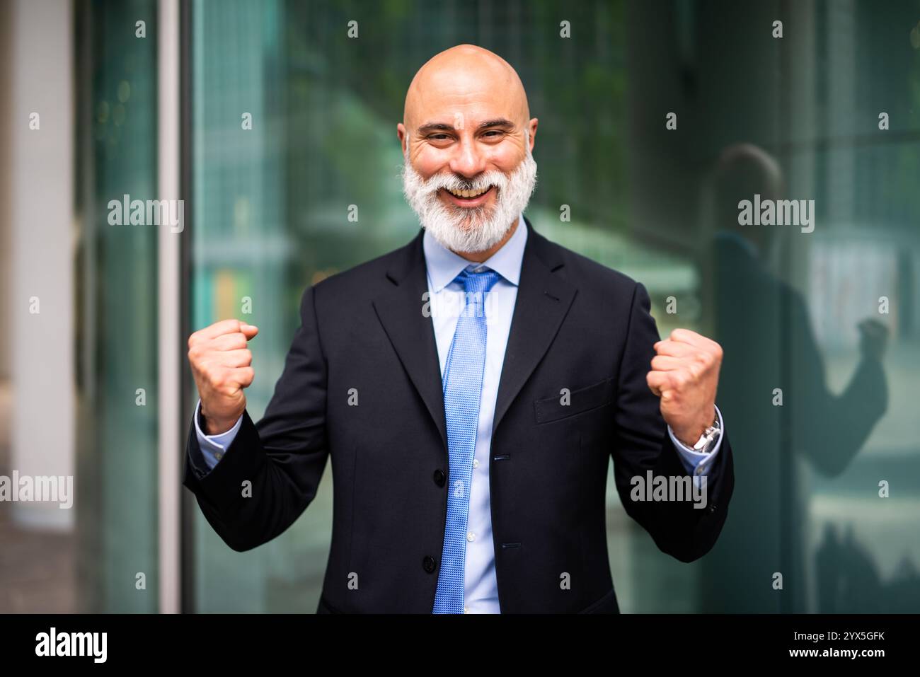 Businessman is raising his fists in the air and smiling, celebrating a ...