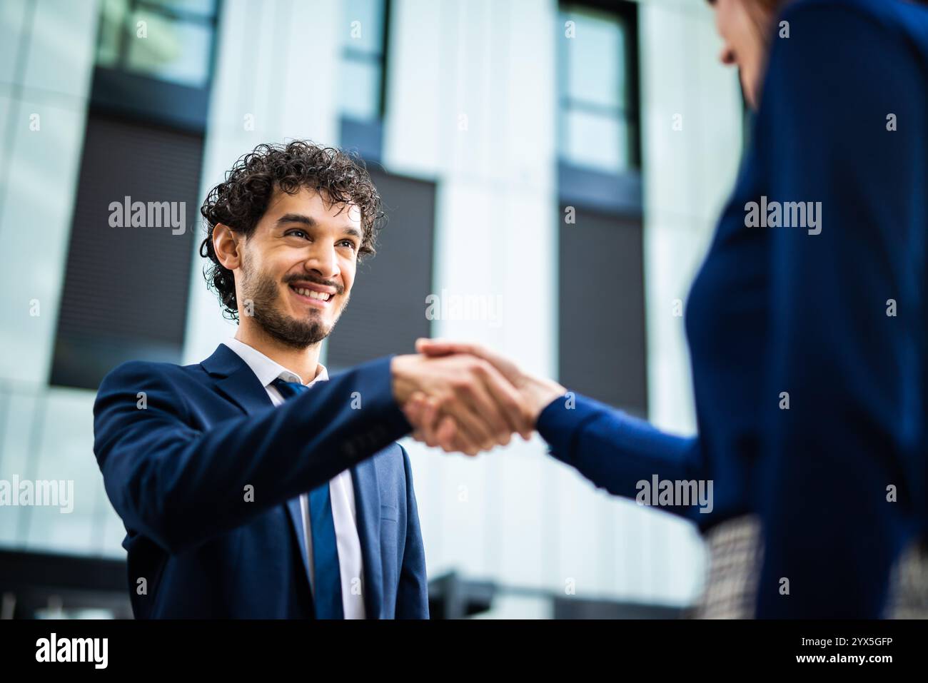 Two business partners shaking hands outside their office building ...