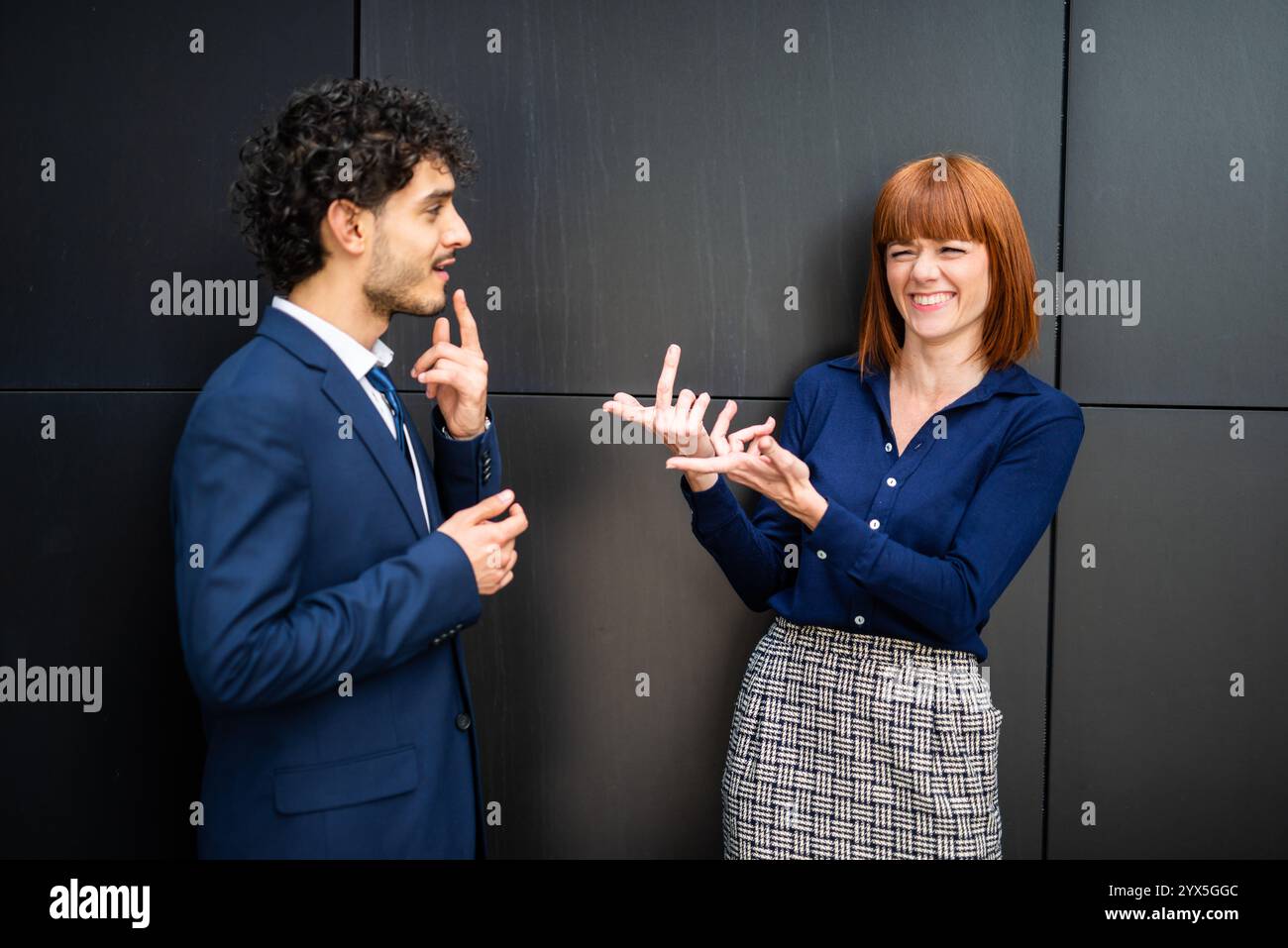 Diverse business duo communicates in sign language outside a modern ...
