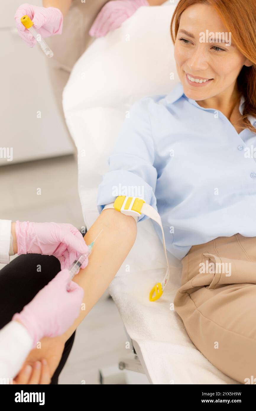 A cheerful woman sits comfortably in a bright clinic while a healthcare ...