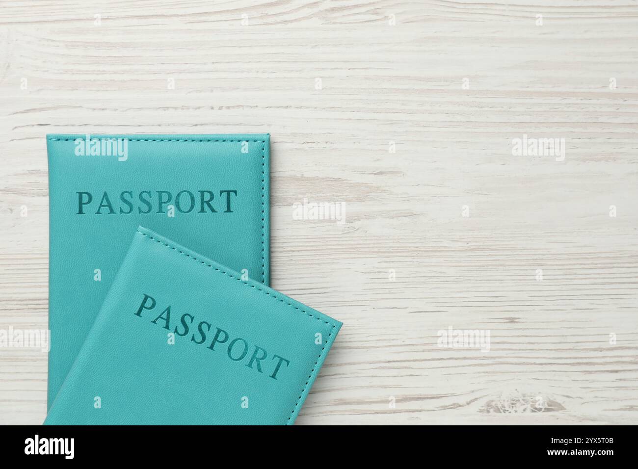 Passports in light blue covers on wooden table, top view. Space for ...