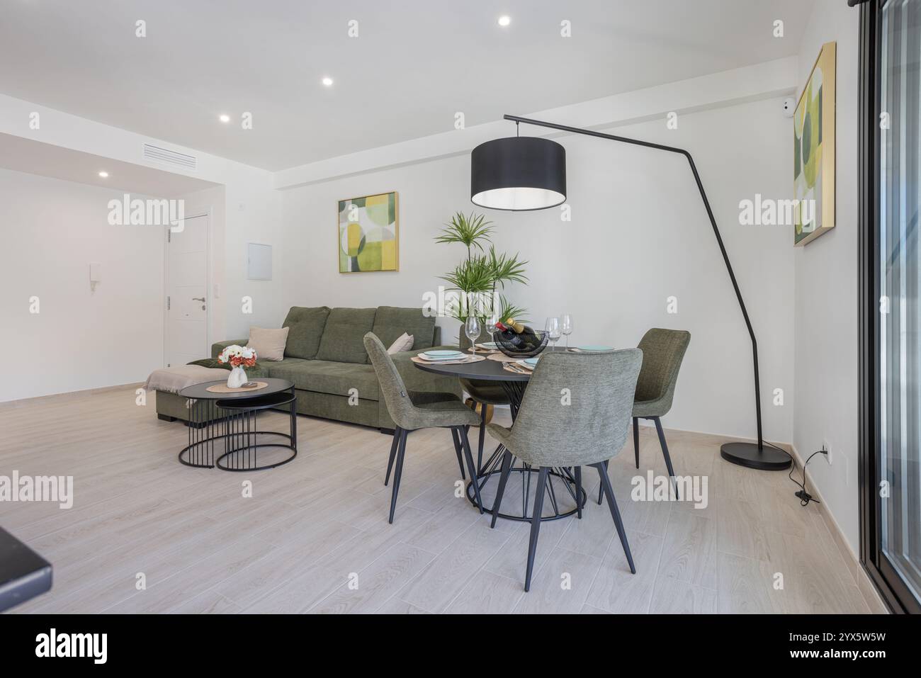 Modern living and dining space featuring a green sofa, round dining ...