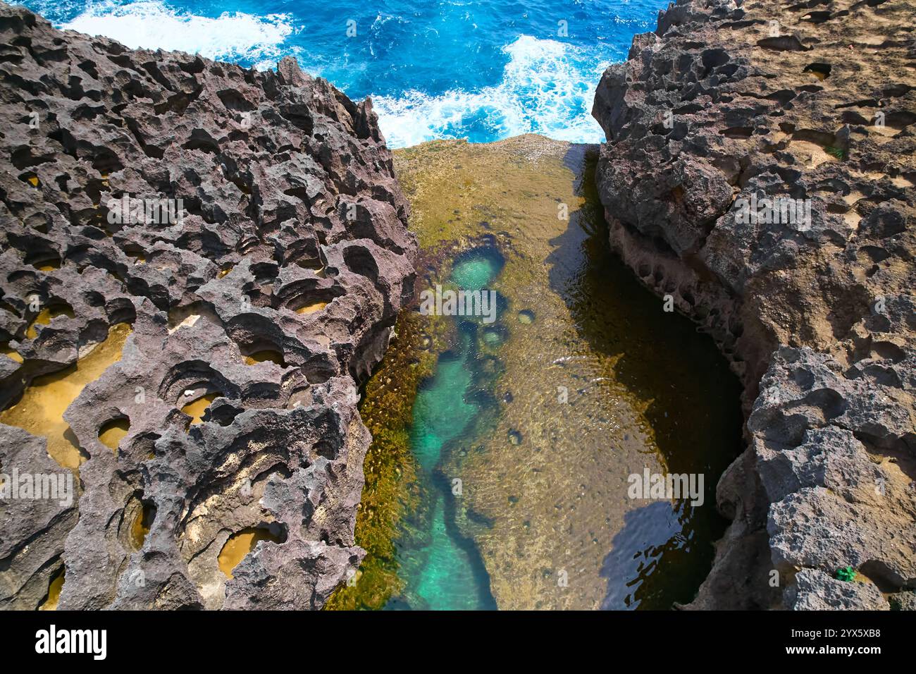 A cliff broken by the wave of the ocean. Natural azure bathing pool in ...