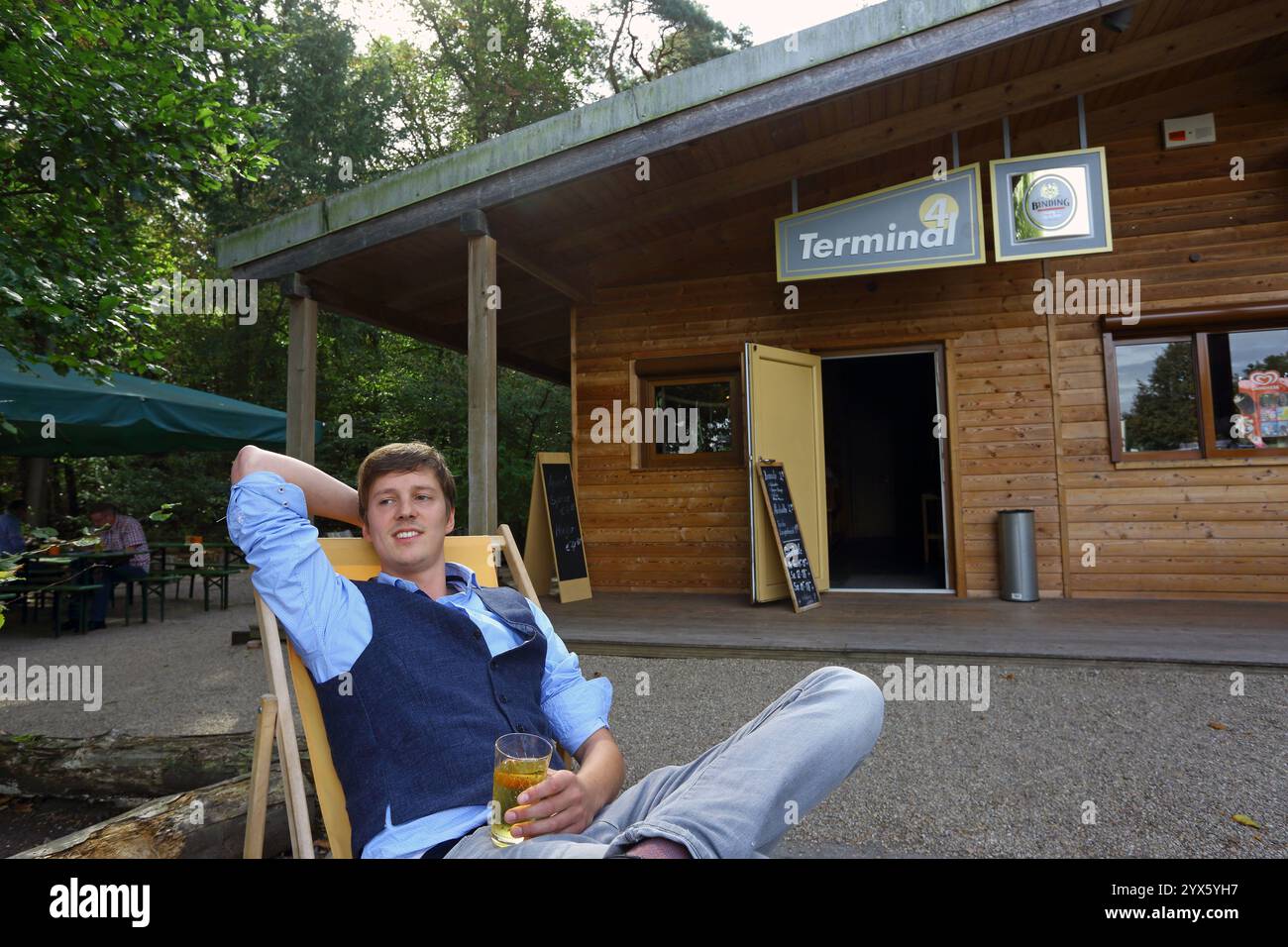 Young man drinking apfelwein a traditional cider drink sitting on chair ...