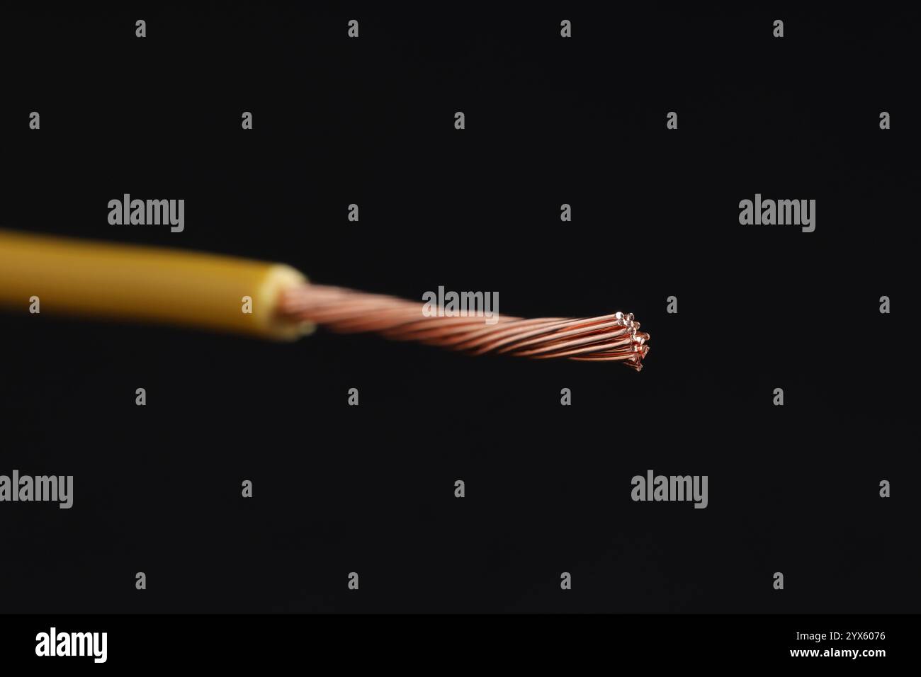 Yellow stripped electrical wire on black background, closeup. Space for ...
