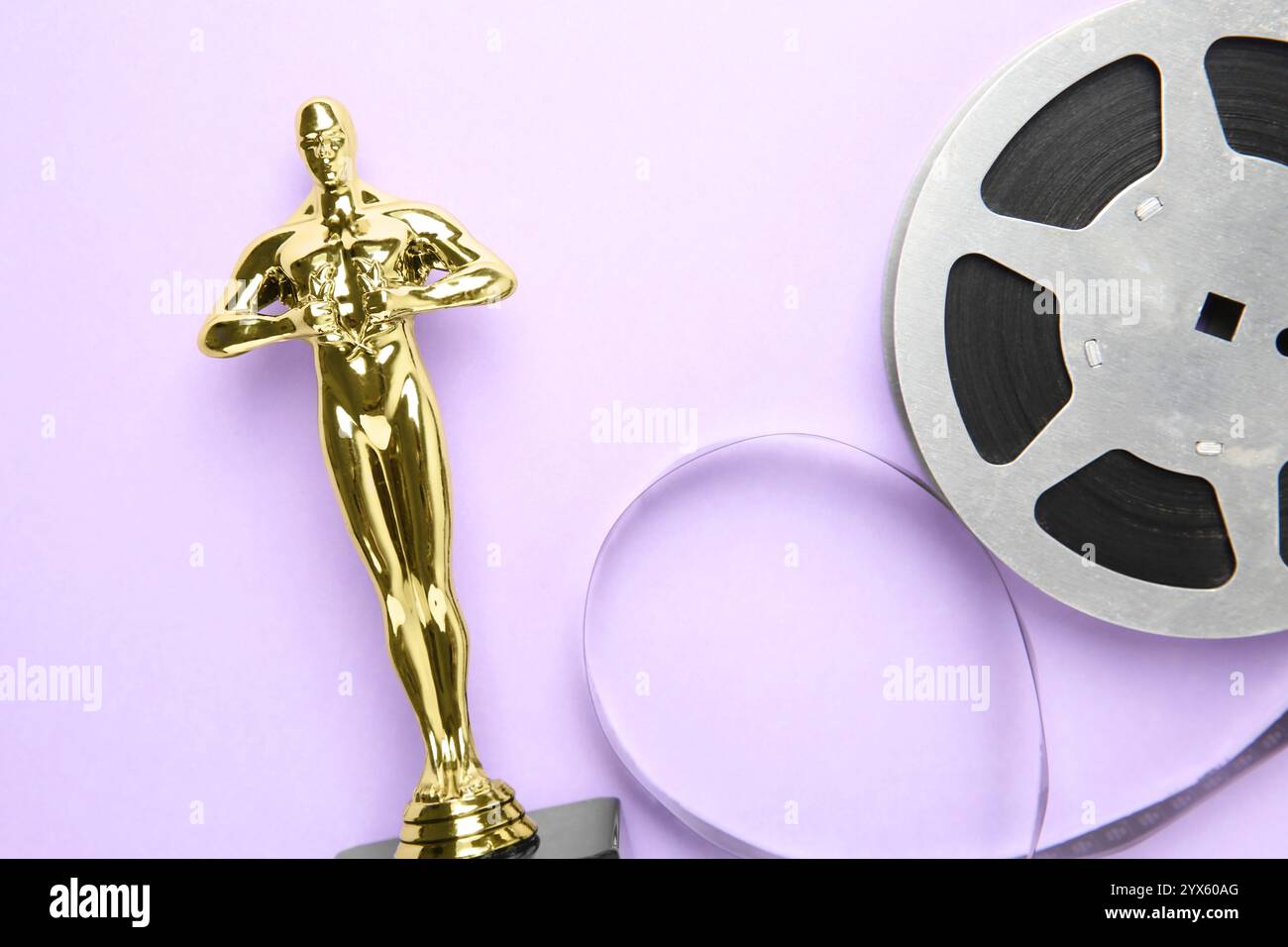 Golden trophy in shape of human figure and film reel on violet ...